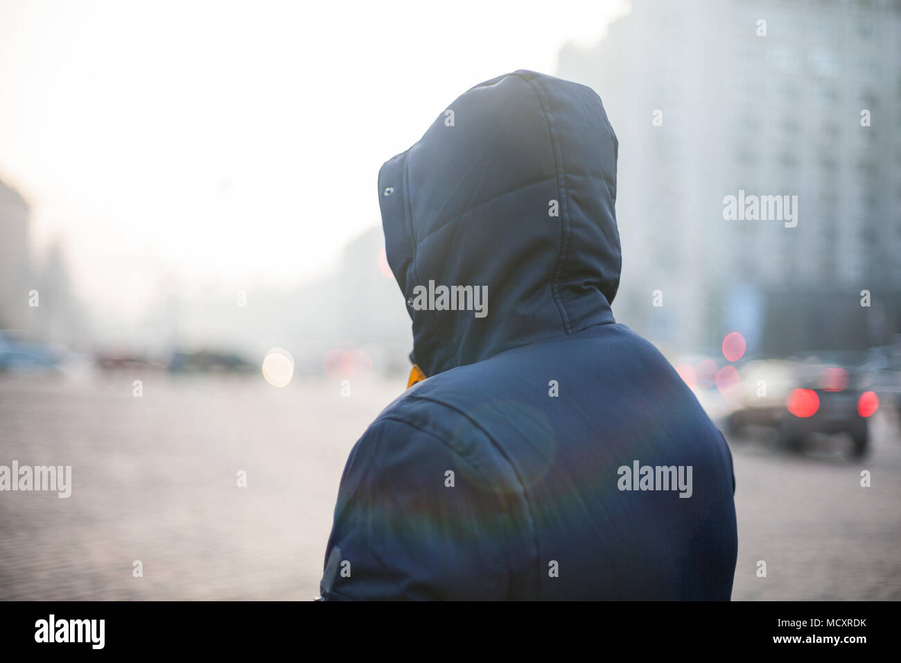 Hipster man in hood walking on city street Stock Photo - Alamy