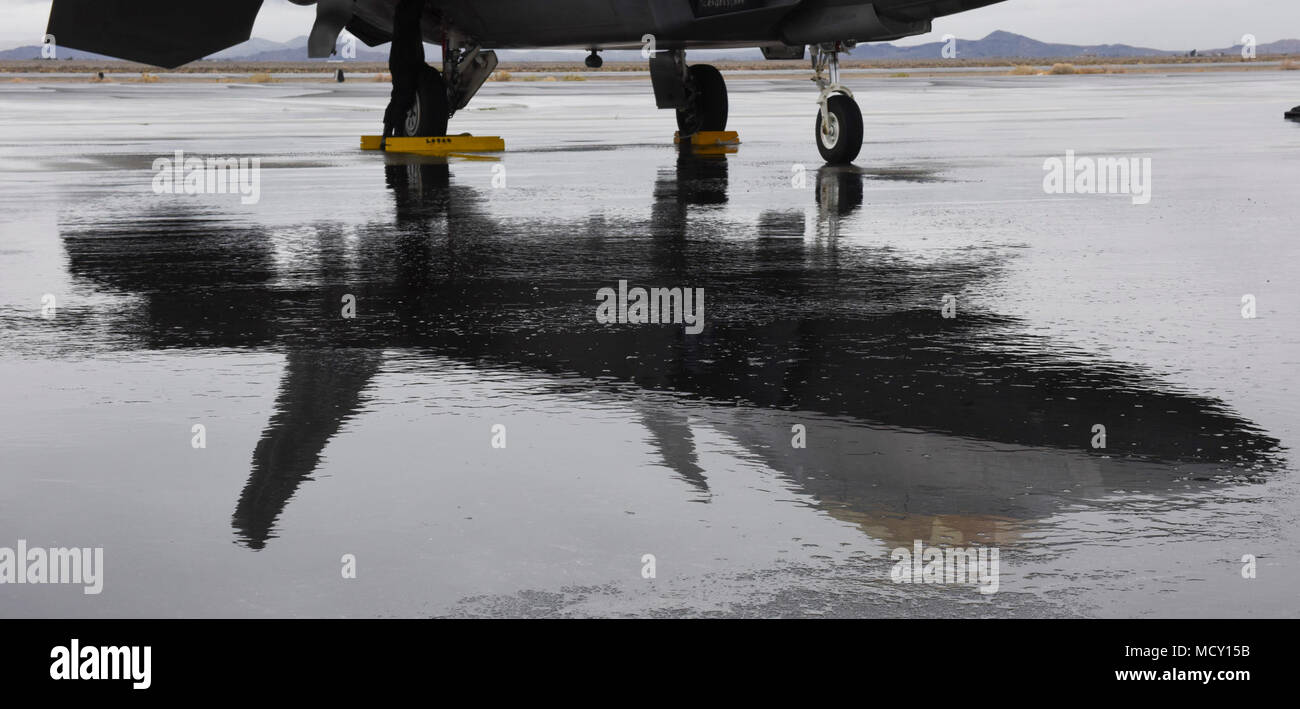 A U.S. Air Force F-22 Raptor reflects on the ground after rainfall at ...