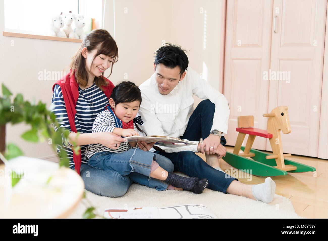 Parents and child reading a book Stock Photo - Alamy