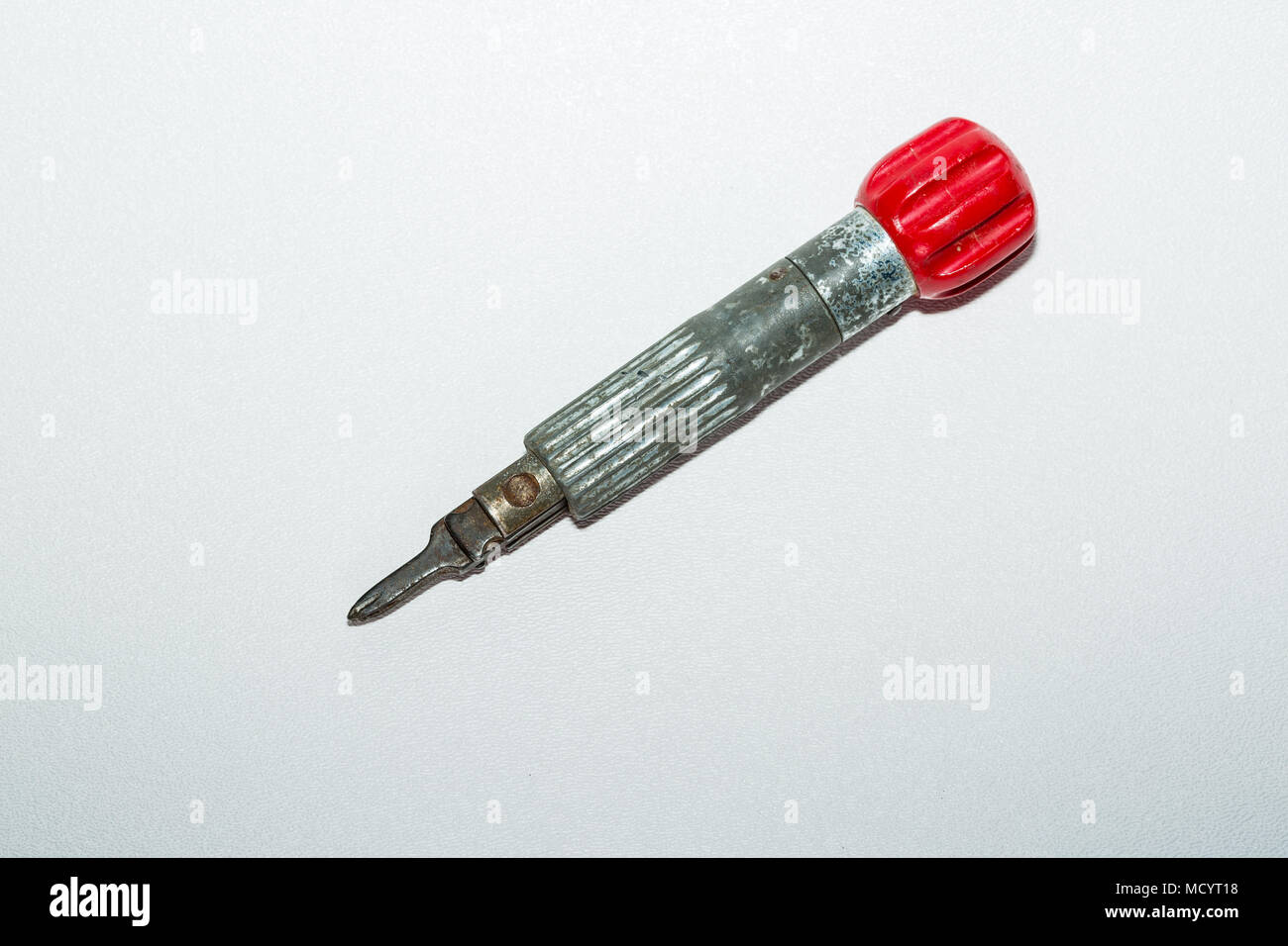 a antique three bladed ratcheting compact screwdriver with a red handle ...