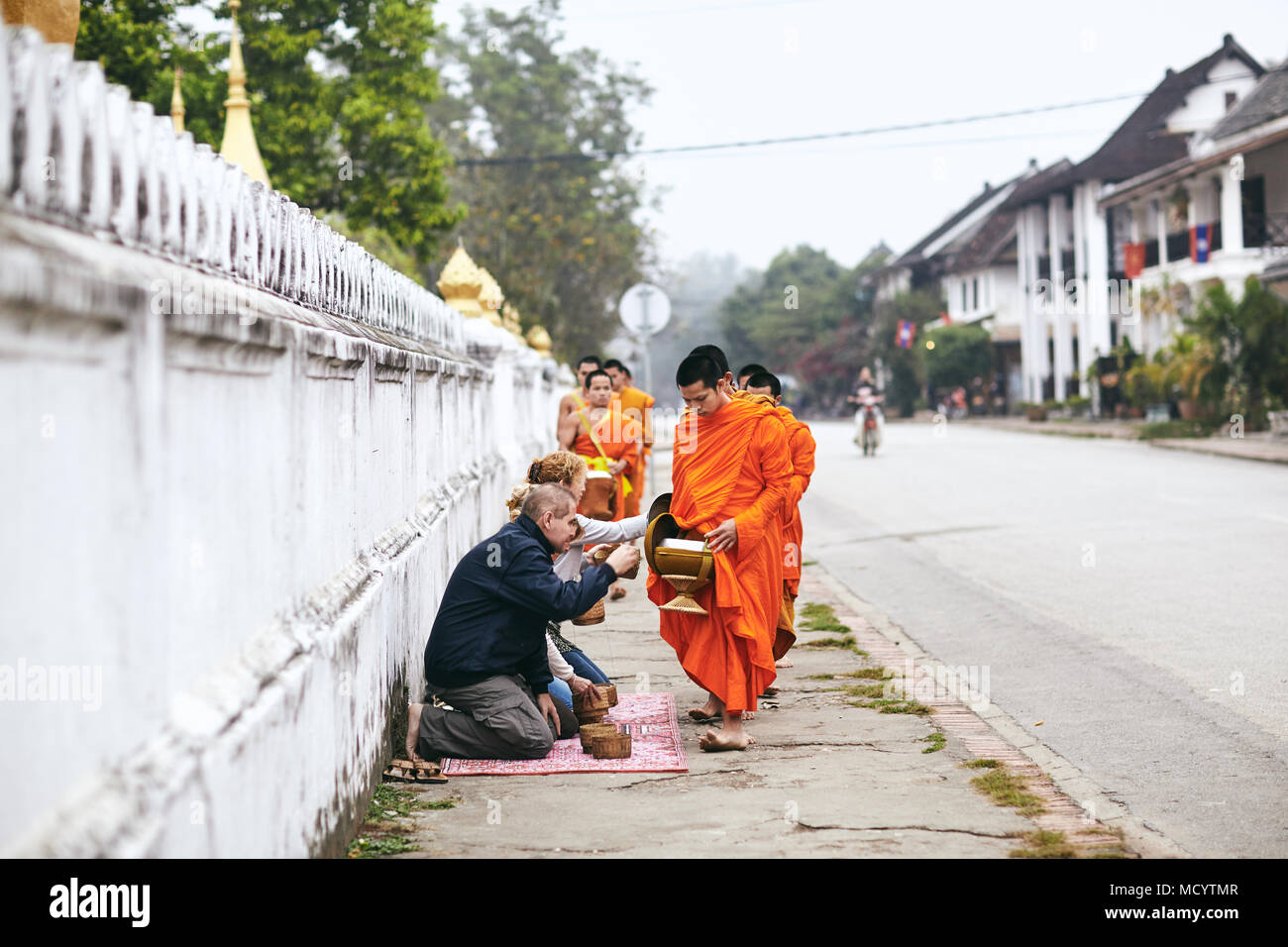 People sitting and offering the food for the monk infront of the temple ...