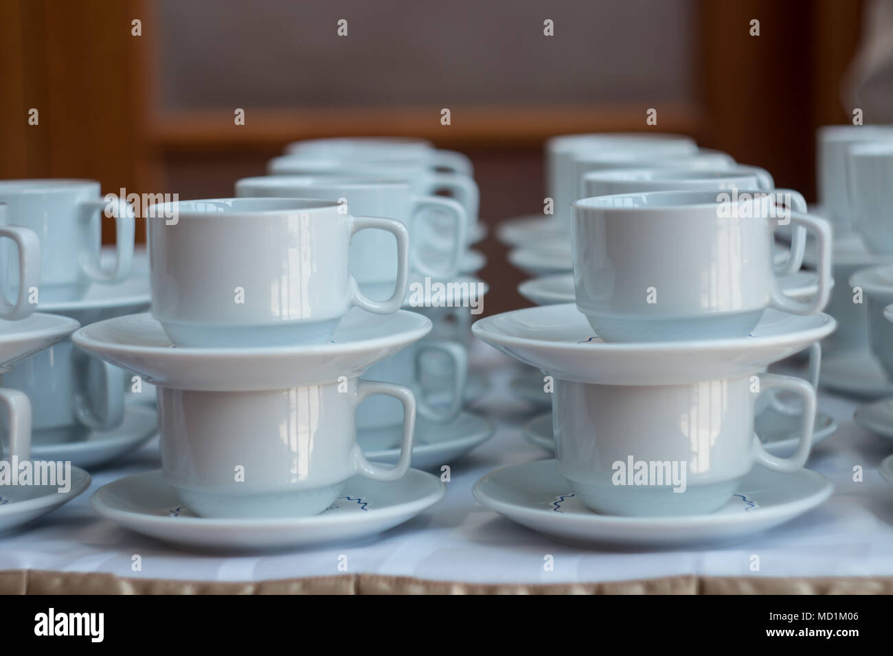 White cups for tea piled on table with plates for coffee-break ...