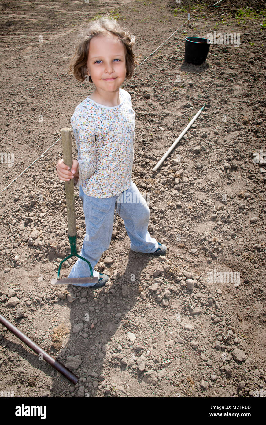 Girl standing with hoe during preparation to plant Stock Photo - Alamy