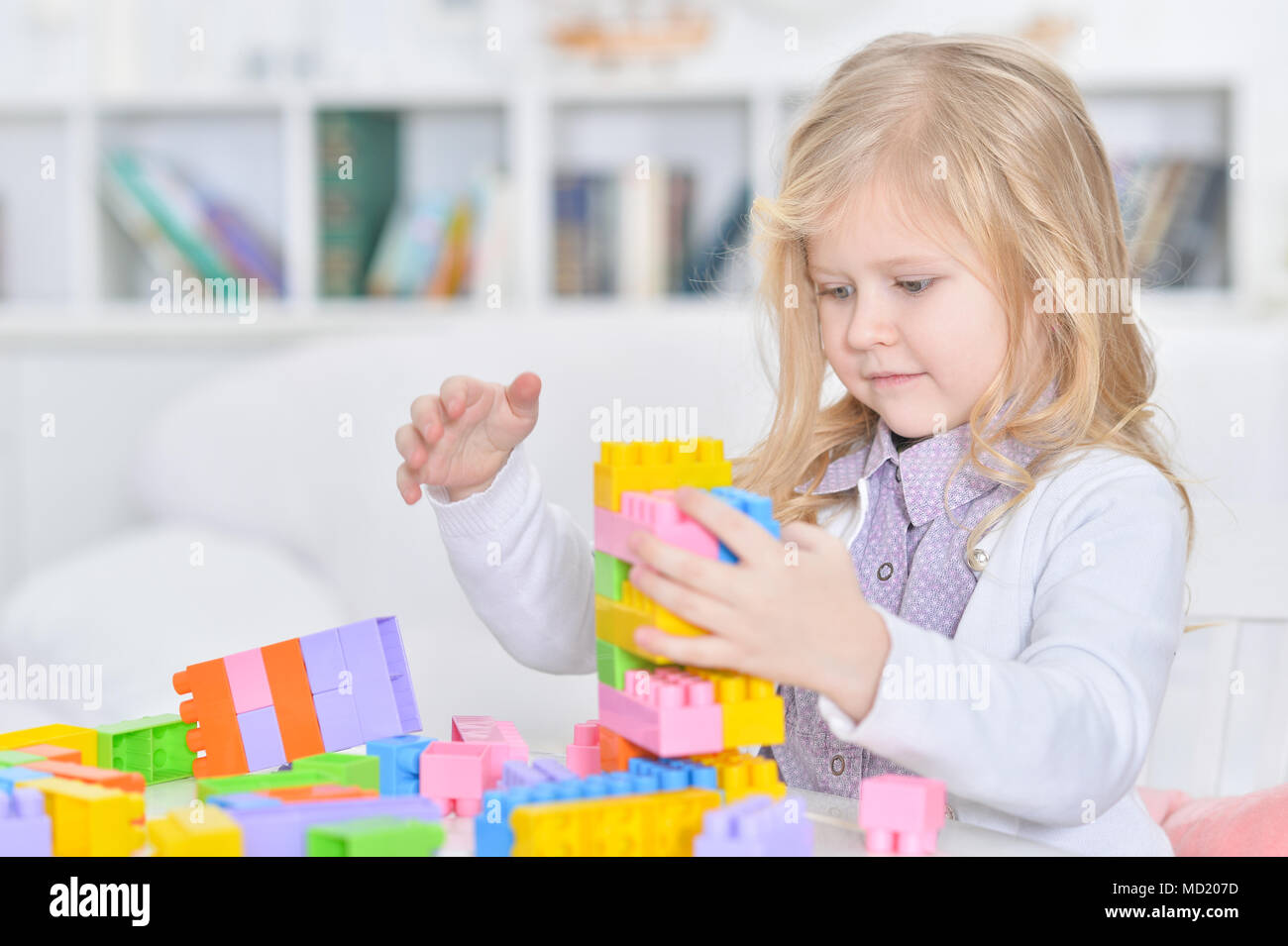 Cute little girl sitting at table and collecting colorful plasti Stock ...