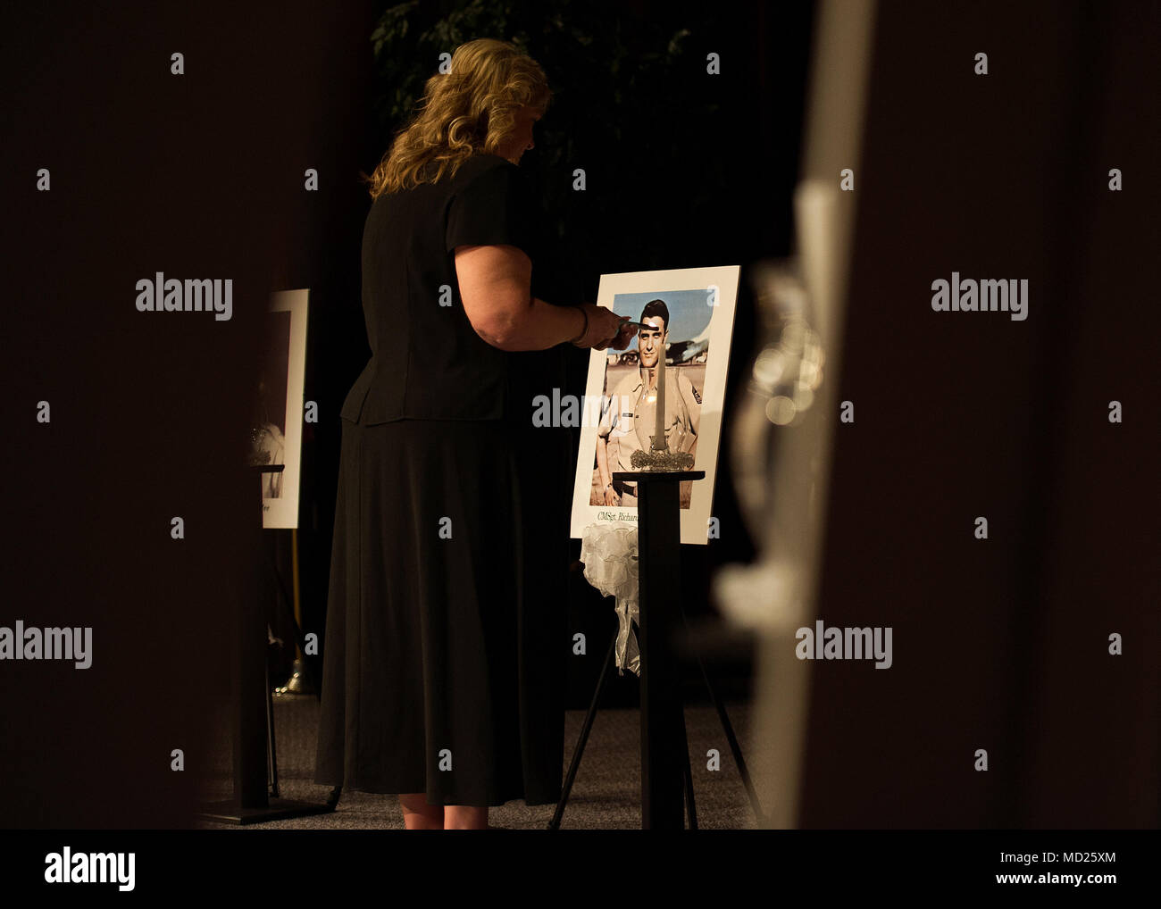 Traci Megennery lights a candle in front of a portrait of her ...