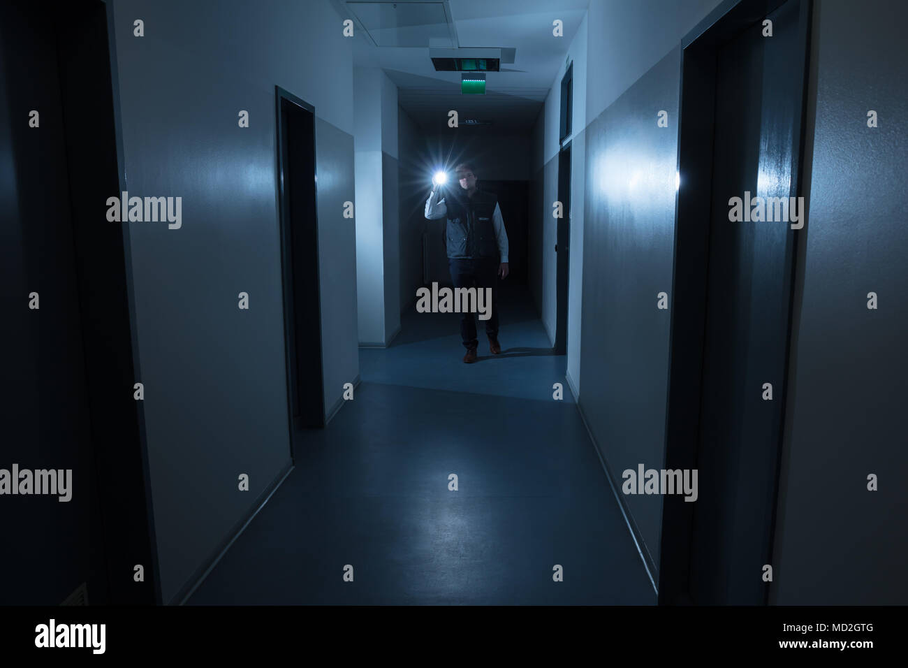Male Security Guard Holding Flashlight Standing In Corridor Of The ...