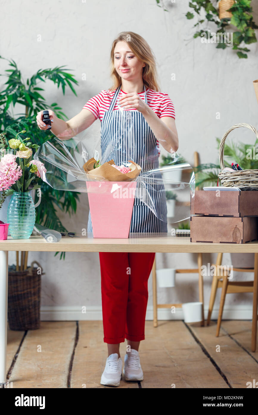 Photo of florist woman with stapler decorating flower arrangement at ...