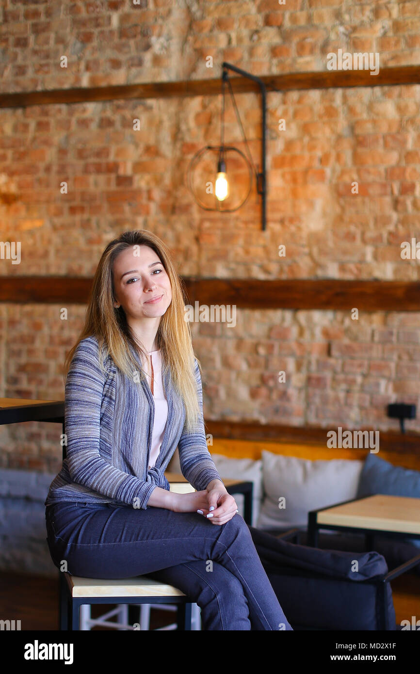 Satisfied girl sitting near table in cozy cafe with unusual interior ...
