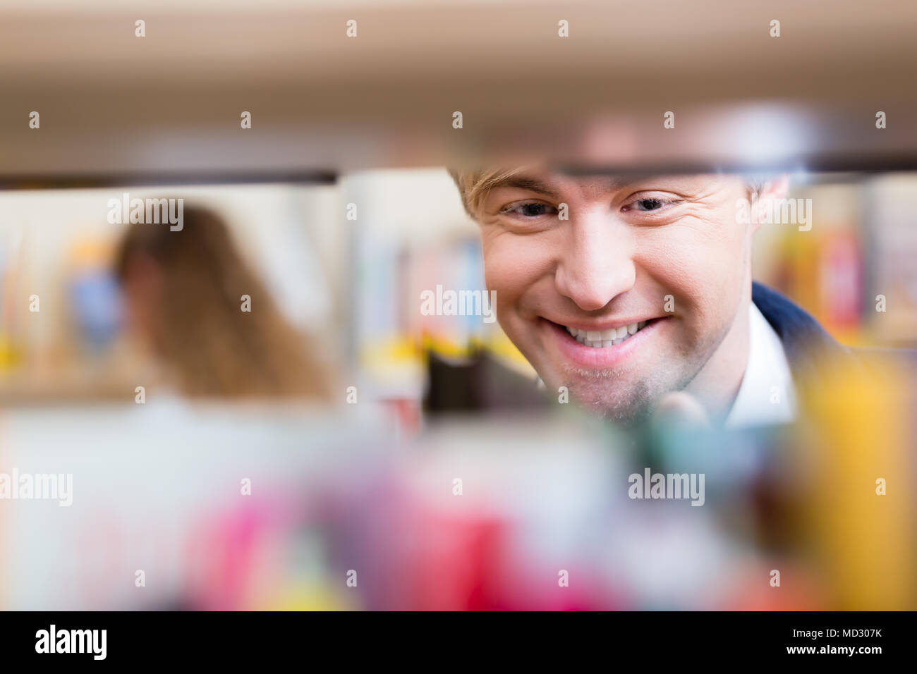 Man looking through shelf of books choosing volume to read in library ...