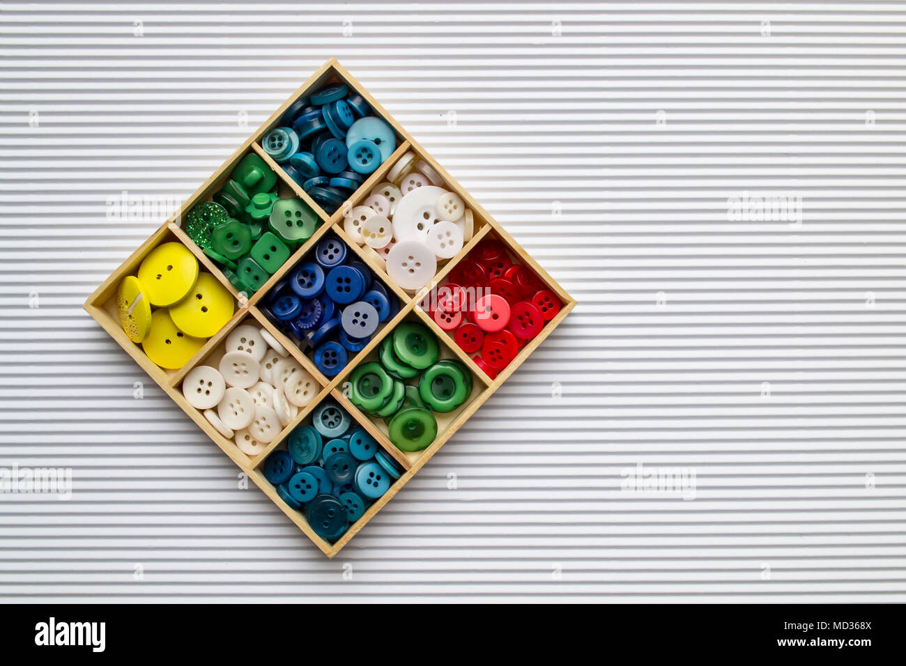 Clothes buttons in wooden box on white cardboard background. Closeup ...