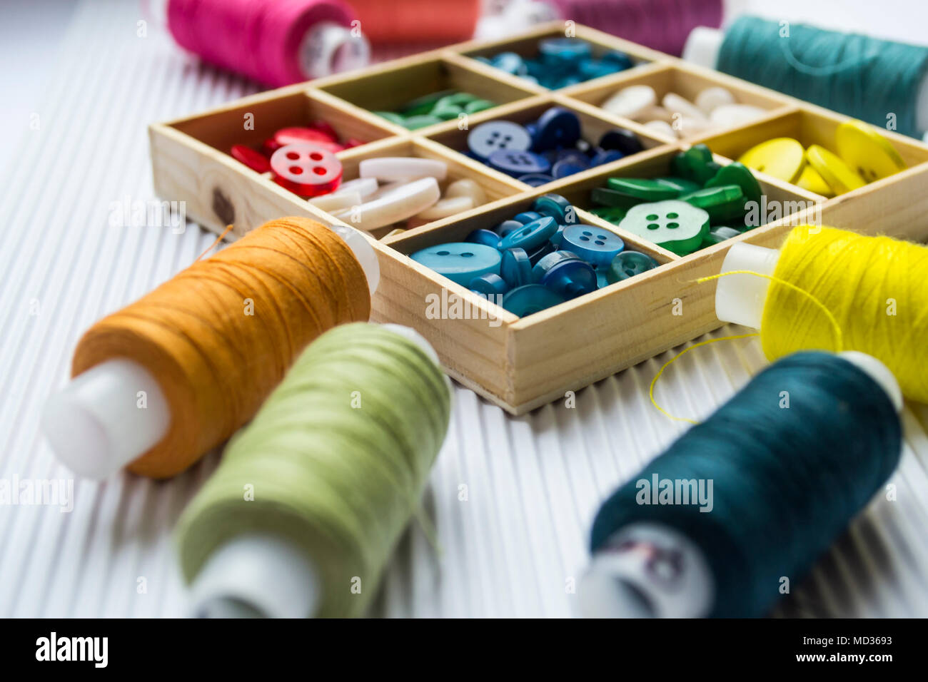 Various colored threads with clothes buttons in wooden box on white ...