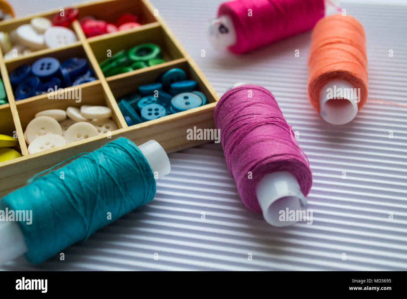 Various colored threads with clothes buttons in wooden box on white ...