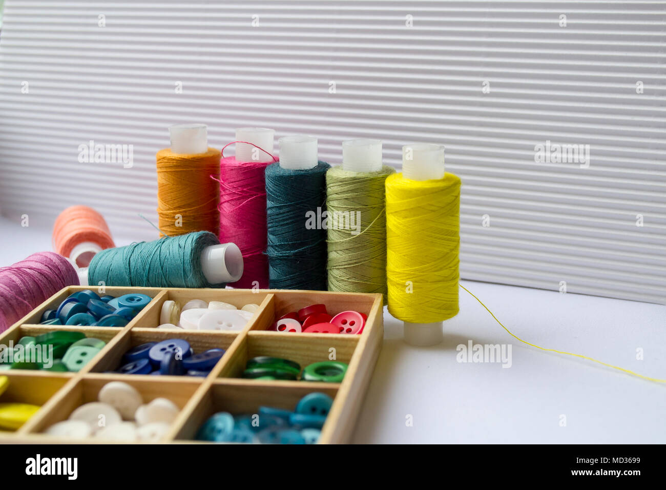 Various colored threads with clothes buttons in wooden box on white ...