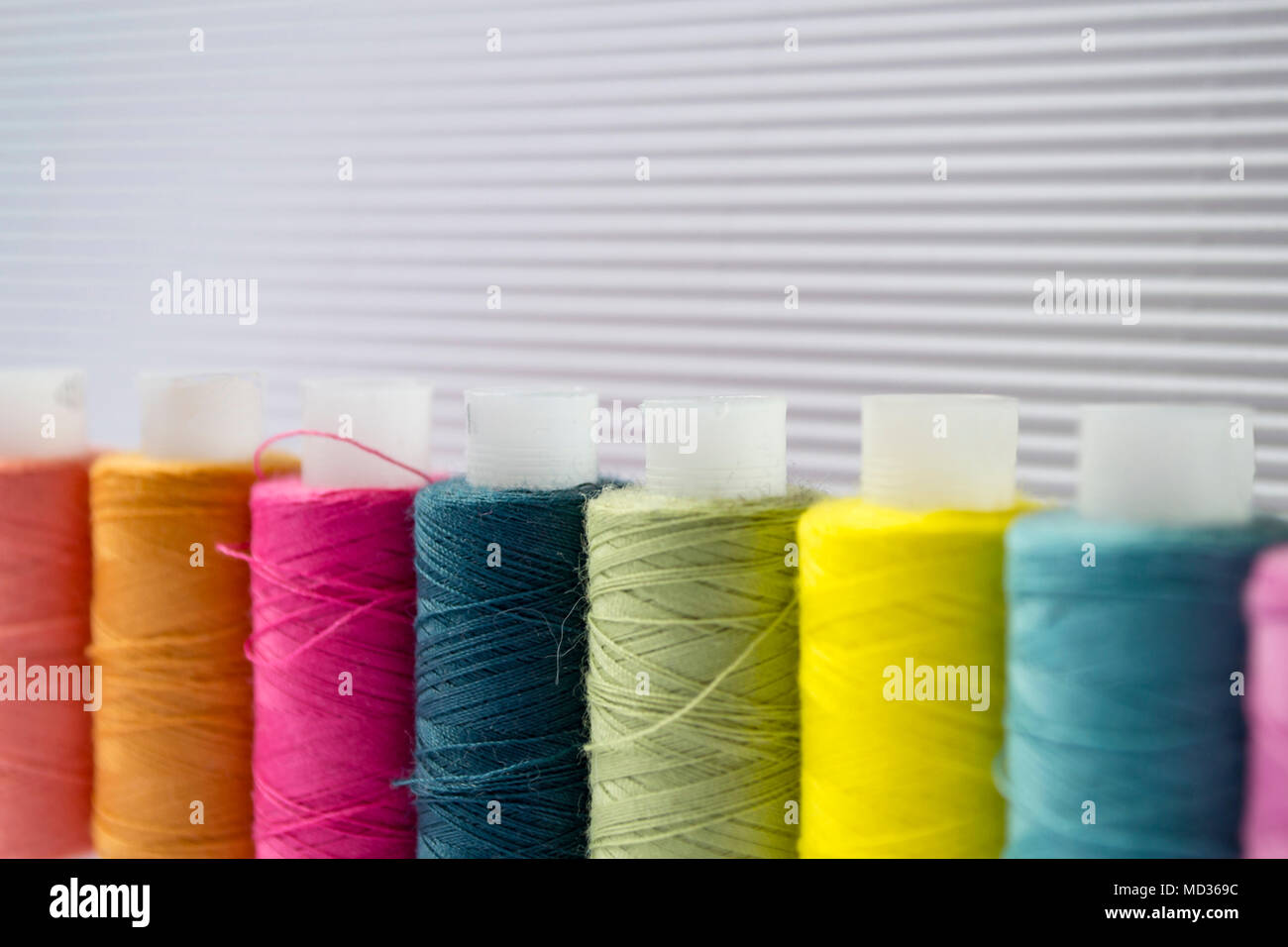 Various colored threads with clothes buttons on white cardboard ...