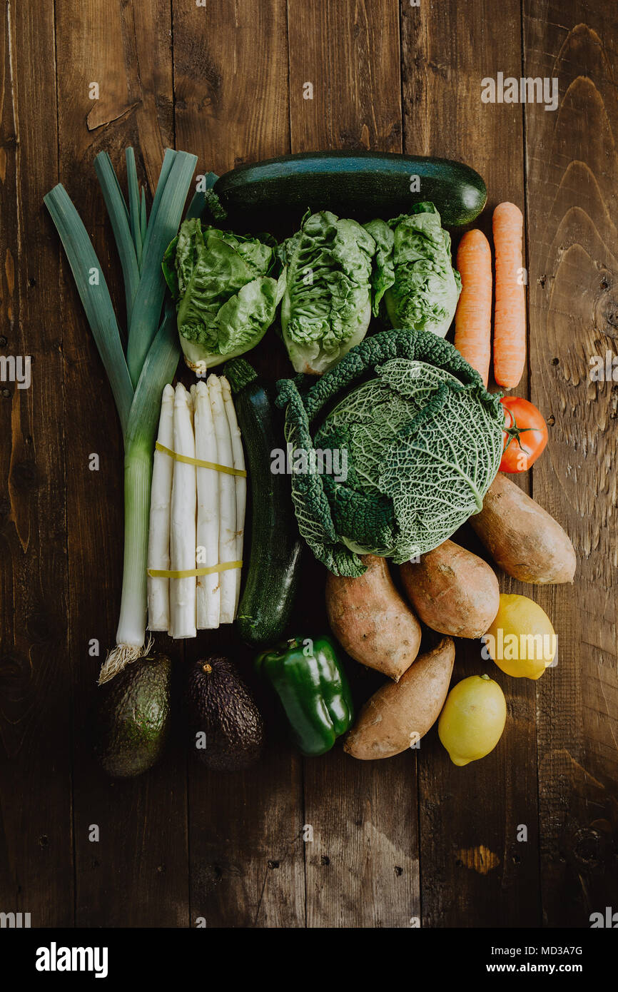Top view of wooden table with healthy green vegetables arranged in pile ...