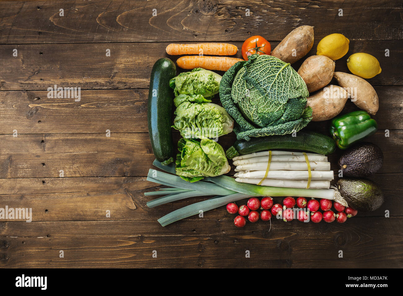 Top view of wooden table with healthy green vegetables arranged in pile ...