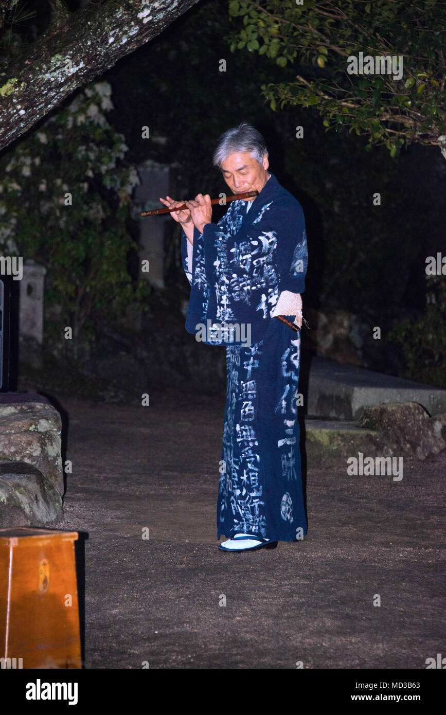 Musician playing flute at night in traditional Japanese dress, Miyajima ...