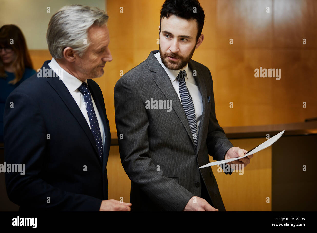 Two businessmen looking at paperwork in reception Stock Photo - Alamy