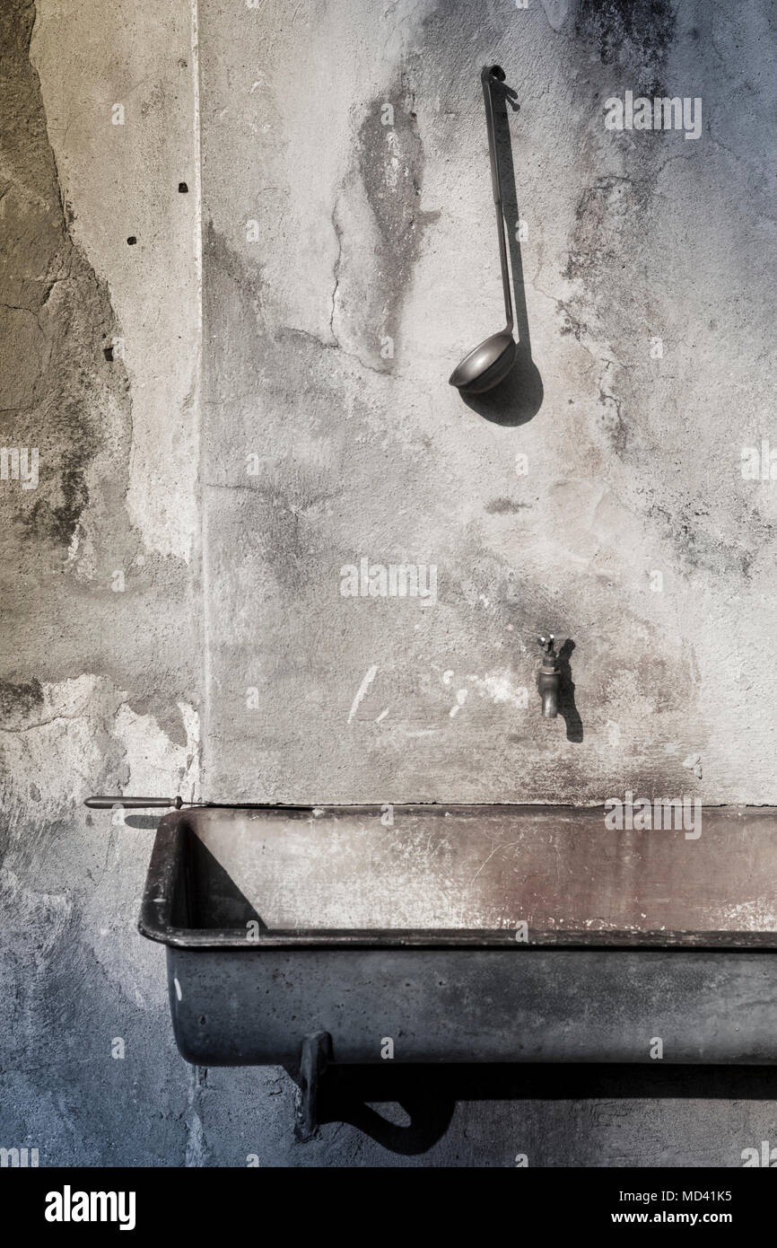 Wall trough and tap with ladle Stock Photo - Alamy