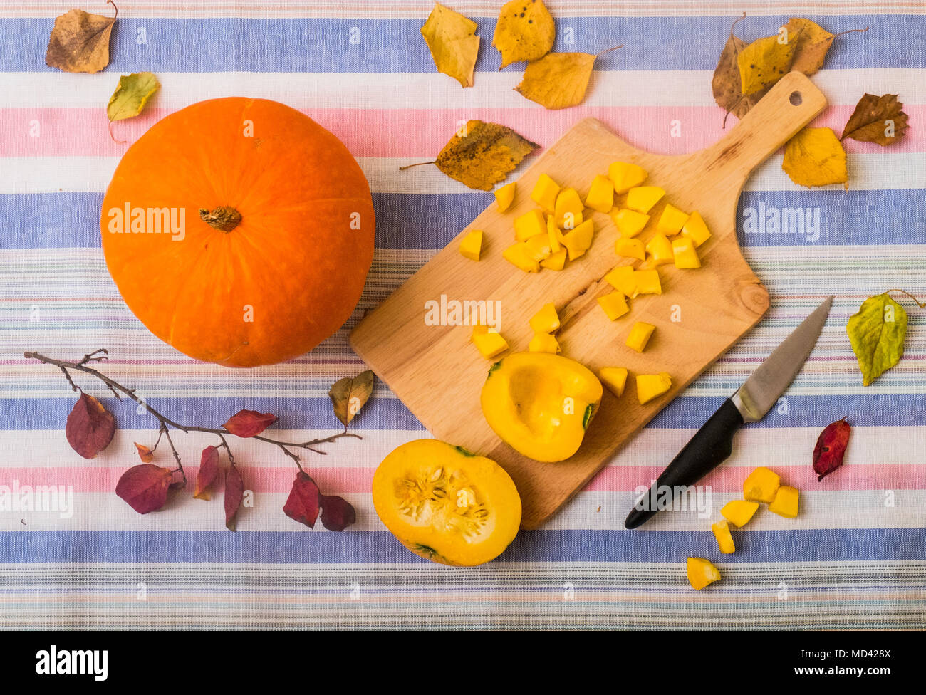 Still life of pumpkin, chopping board and chopped pumpkin, overhead ...