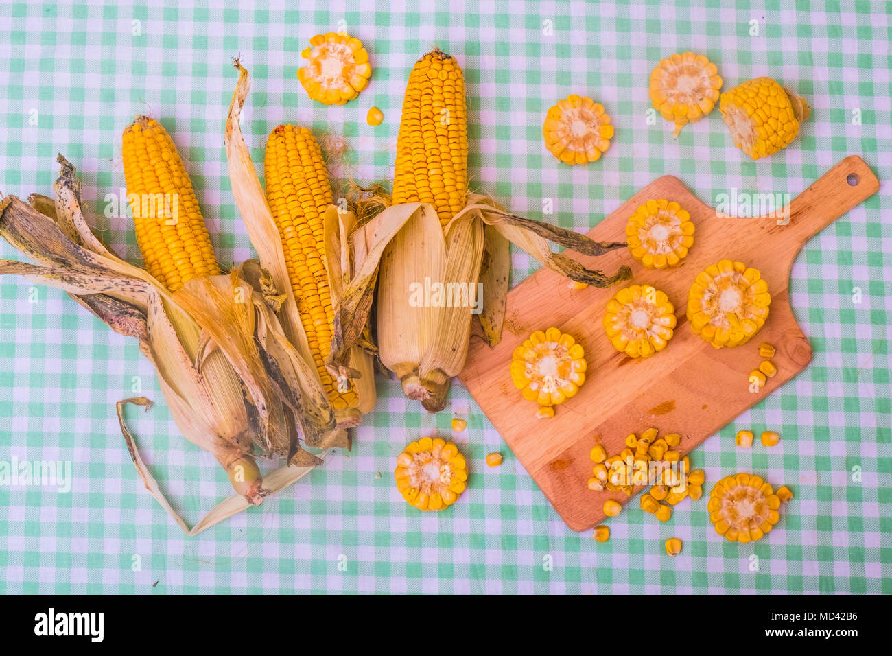 Sliced corn on the cob on chopping board, with whole corn on cob ...