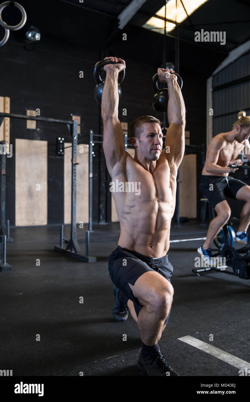 Two men exercising in gymnasium, using kettlebells and air resistance ...