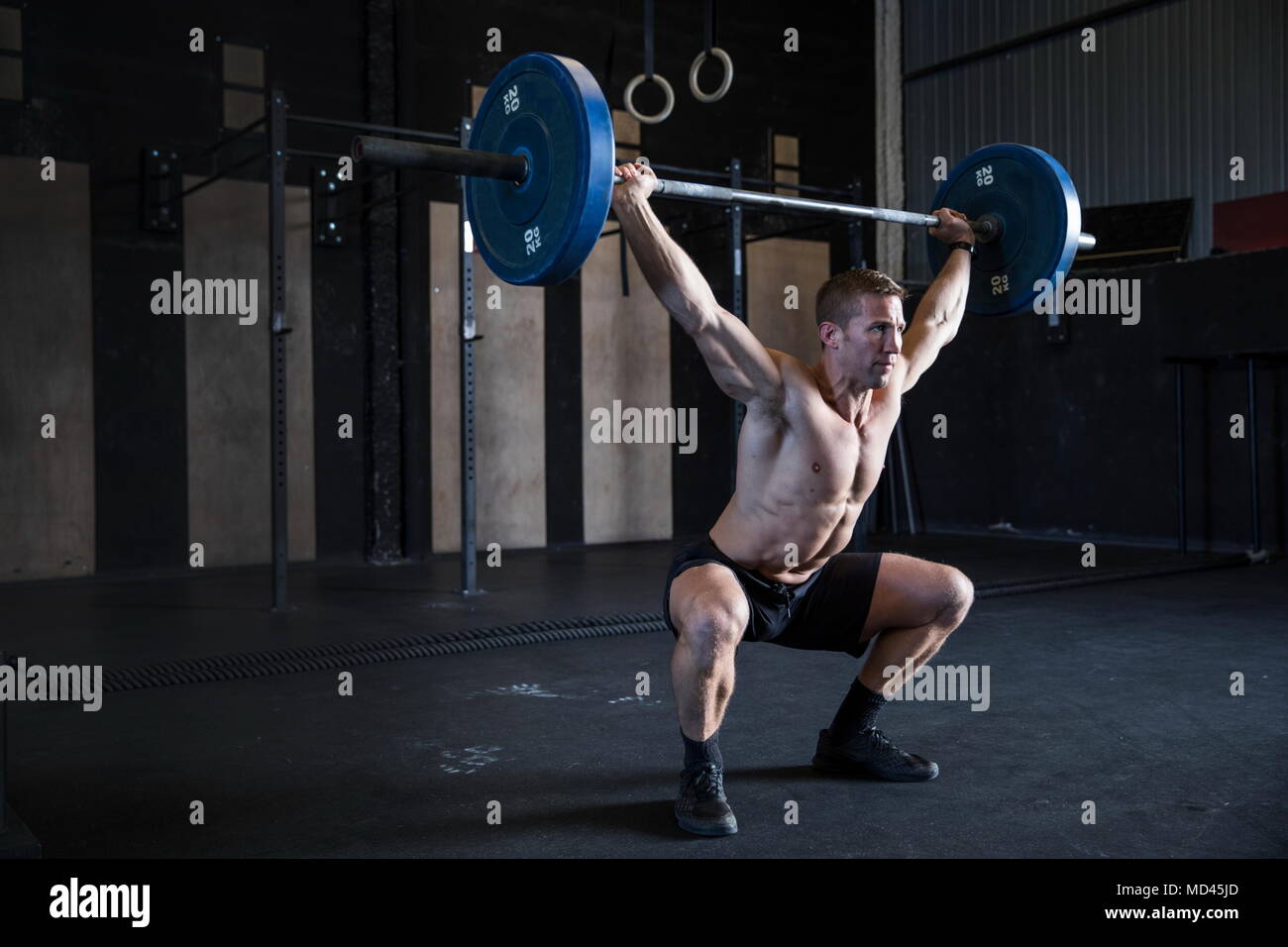 Man exercising in gym, using barbell, front squat position Stock Photo ...