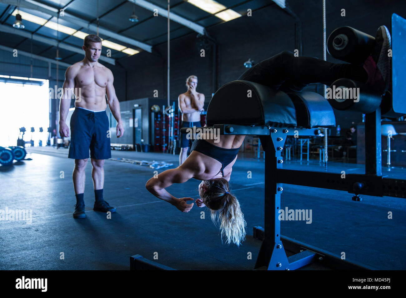 Three people exercising in gymnasium, using equipment Stock Photo - Alamy