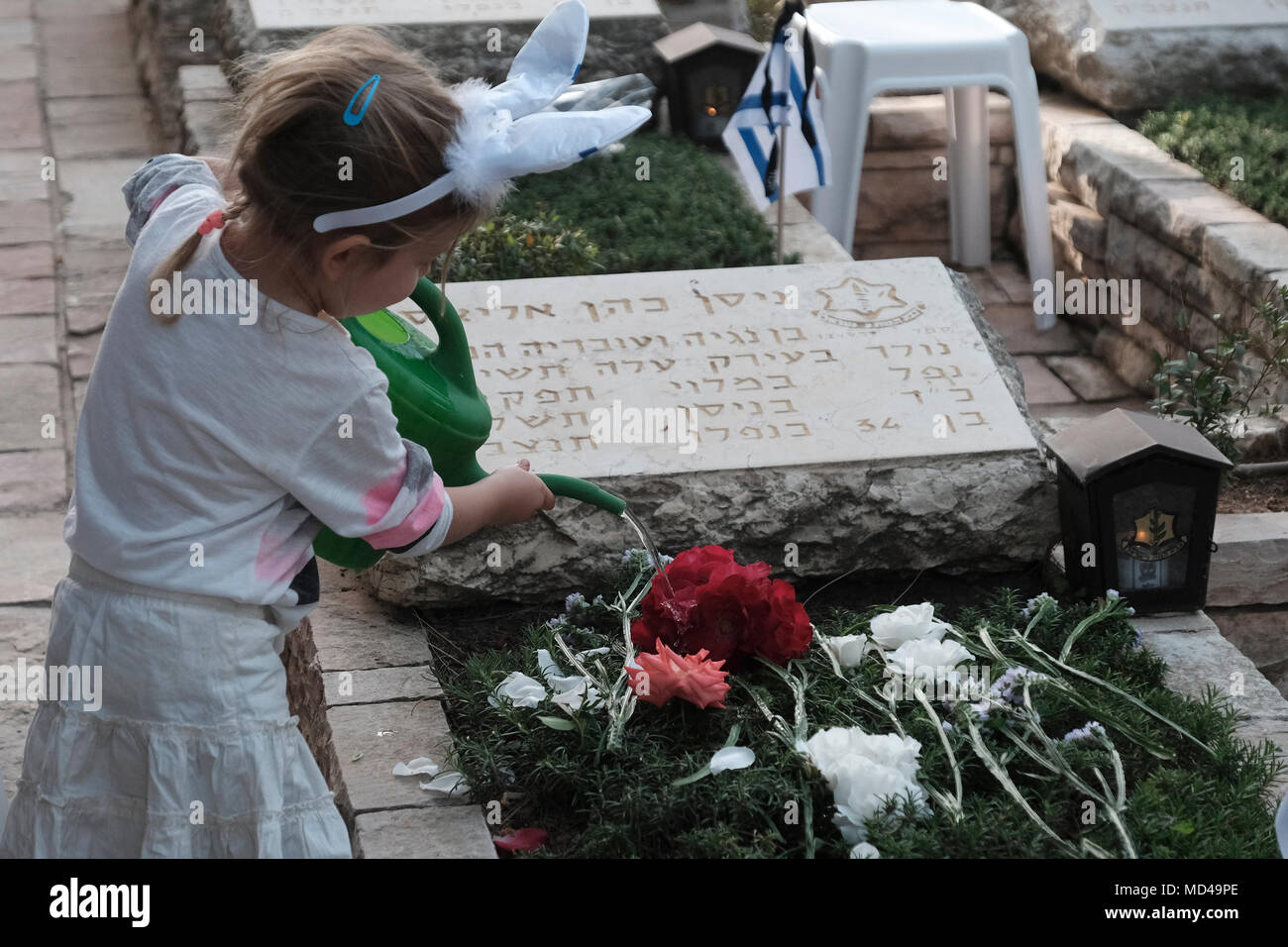 A young girl watering flowers at the grave of an Israeli fallen soldier ...