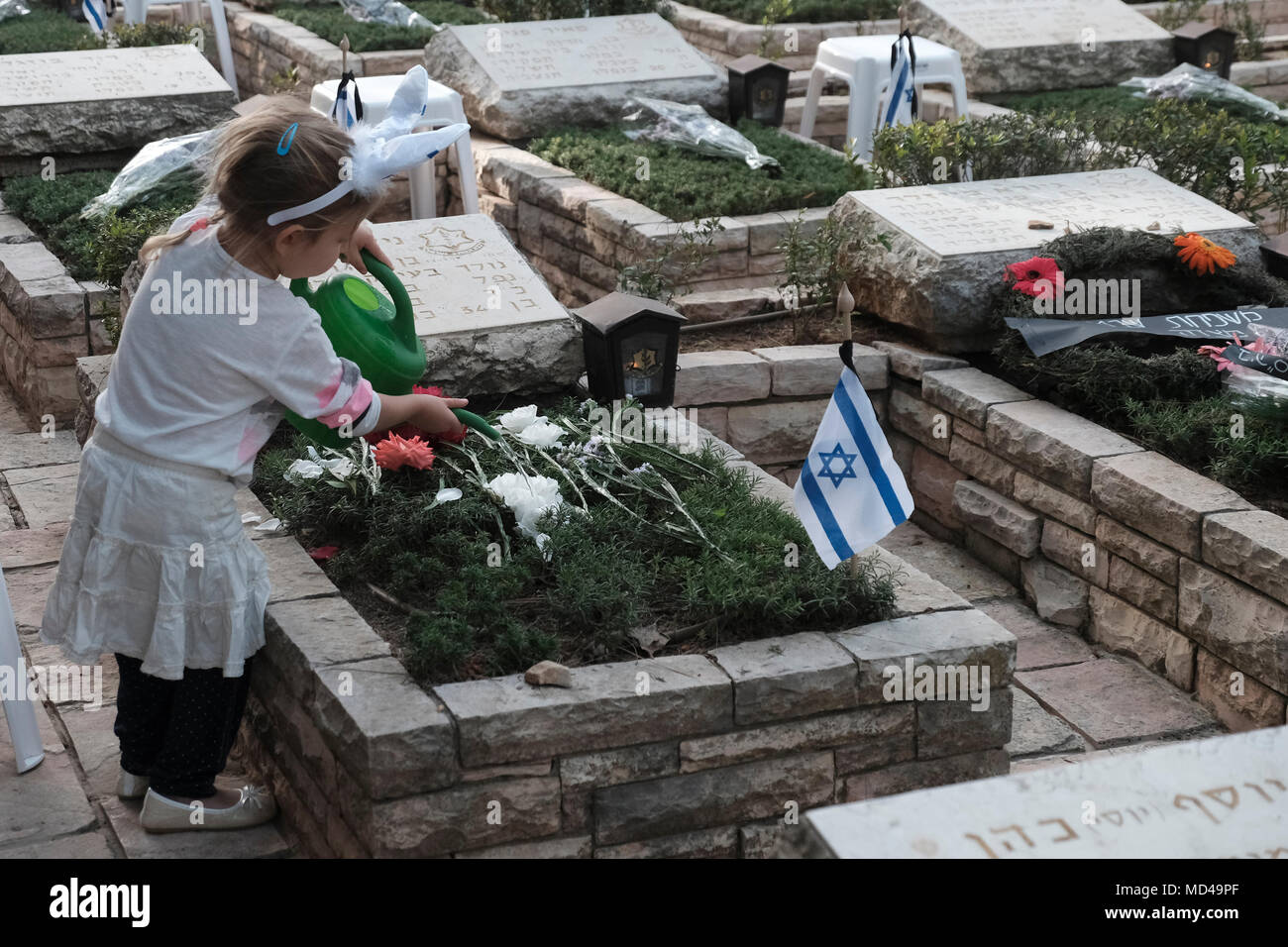 A young girl watering flowers at the grave of an Israeli fallen soldier ...