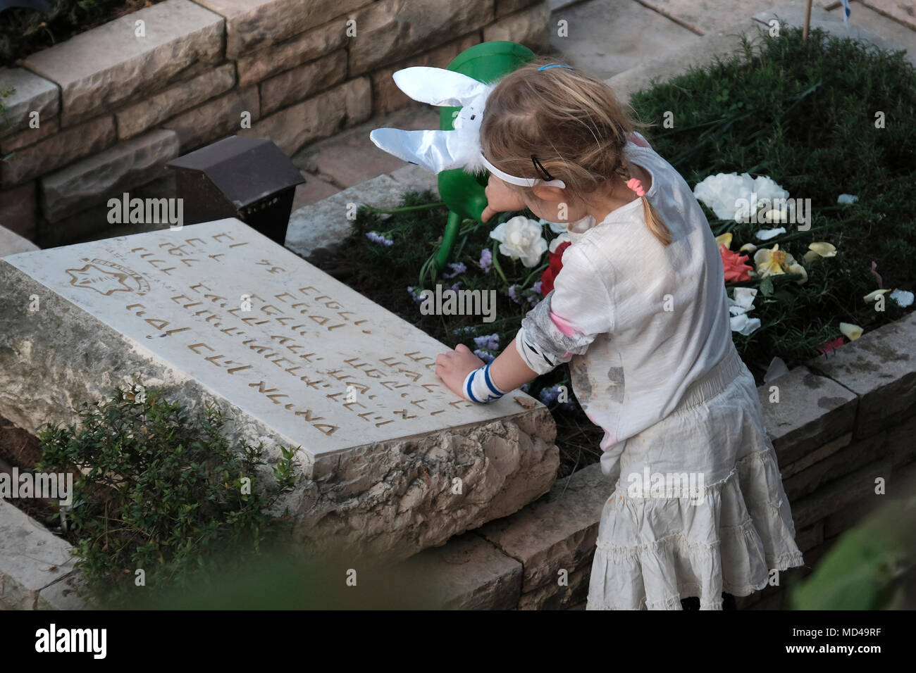 A young girl watering flowers at the grave of an Israeli fallen soldier ...