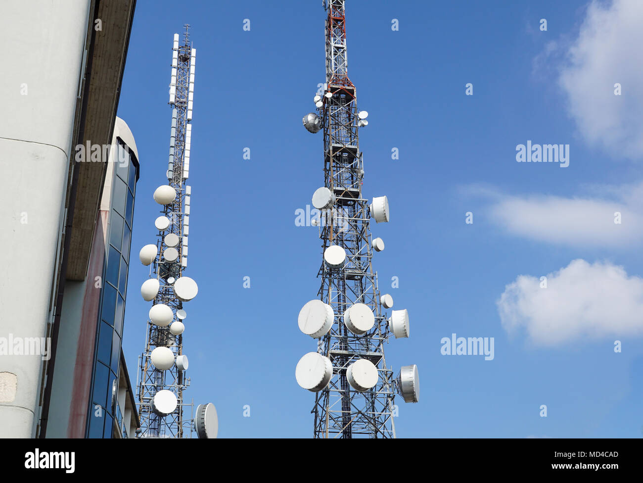Mobile phone communication antenna tower with satellite dish on blue sky background ...