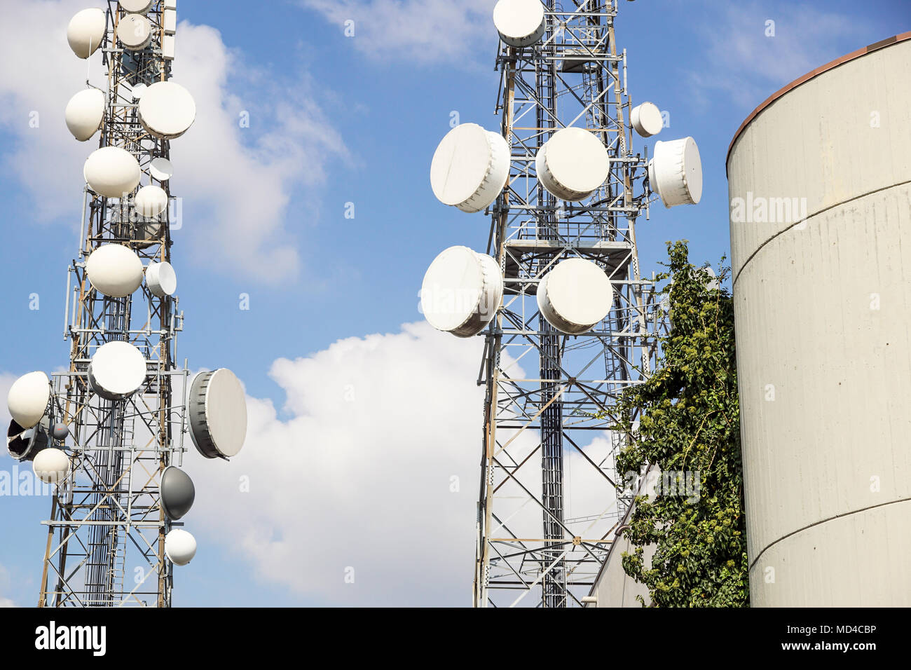 Mobile phone communication antenna tower with satellite dish on blue ...