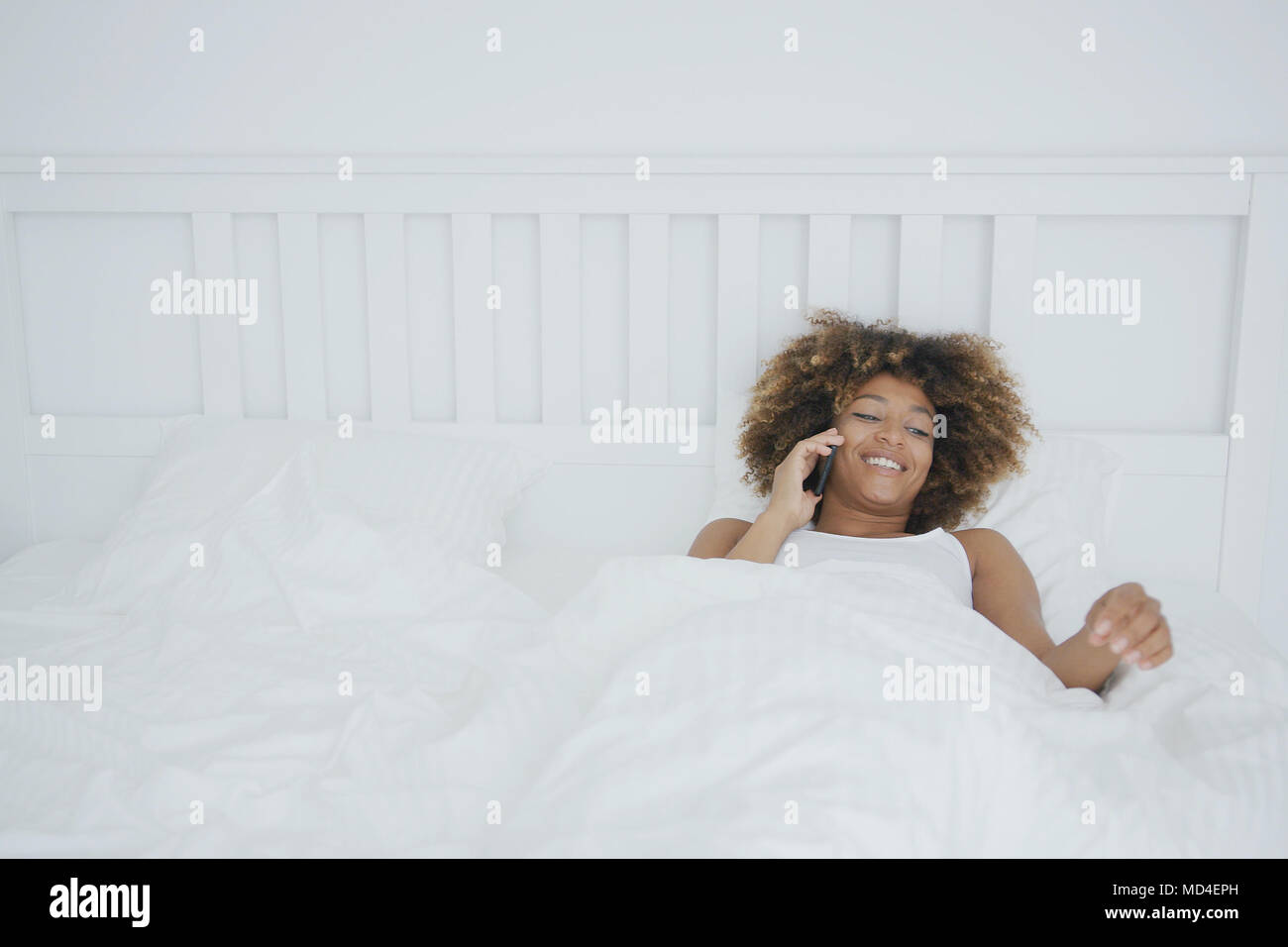 Smiling woman in bed having phone call Stock Photo - Alamy