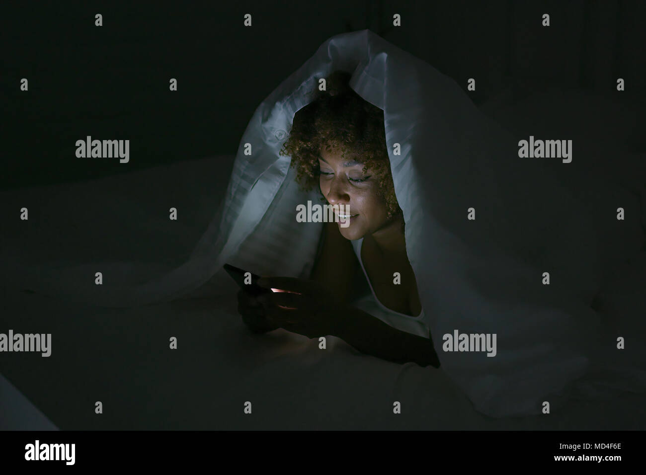 Young woman using phone in dark room Stock Photo - Alamy