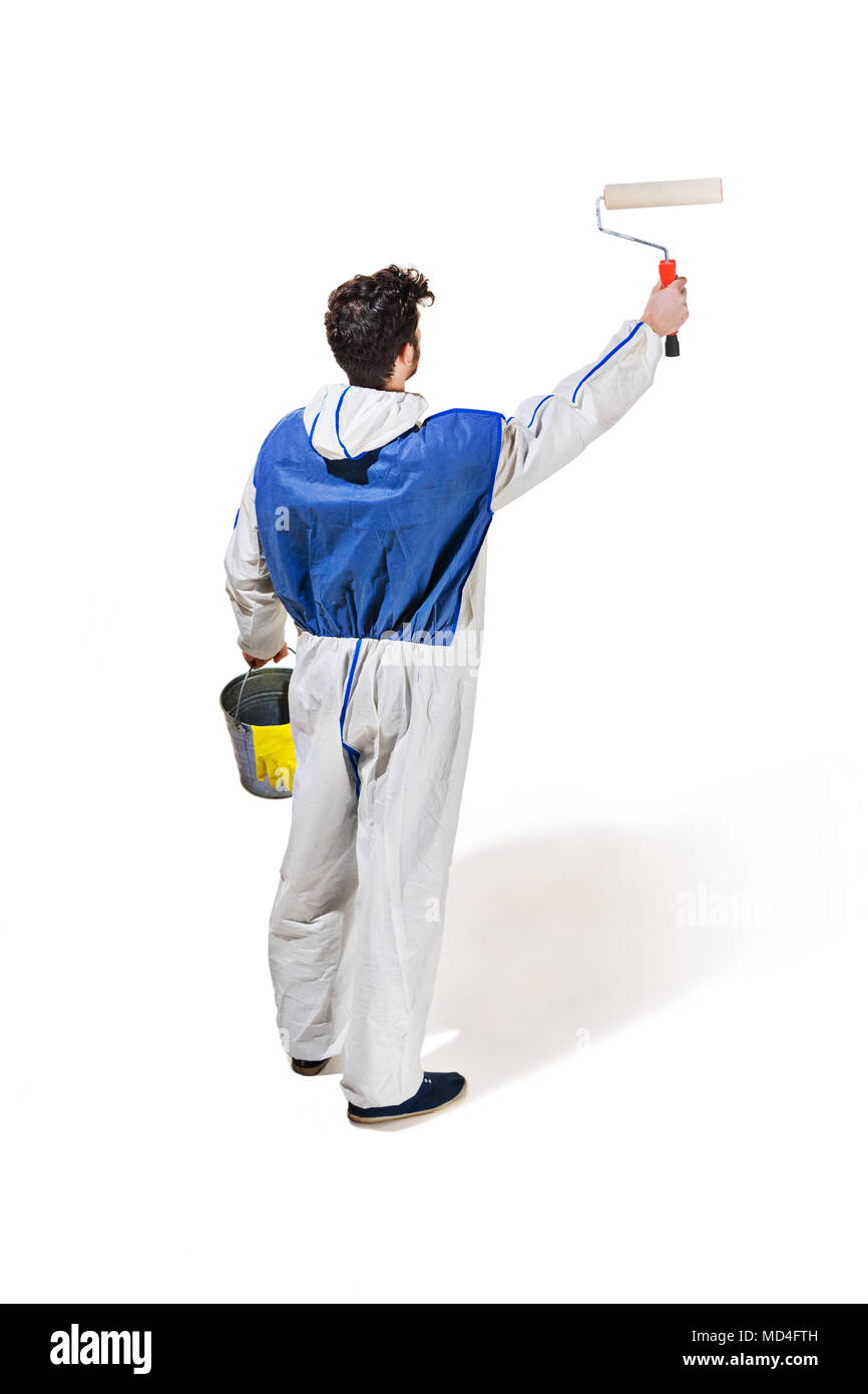 Young male decorator painting with a paint roller climbed a ladder ...