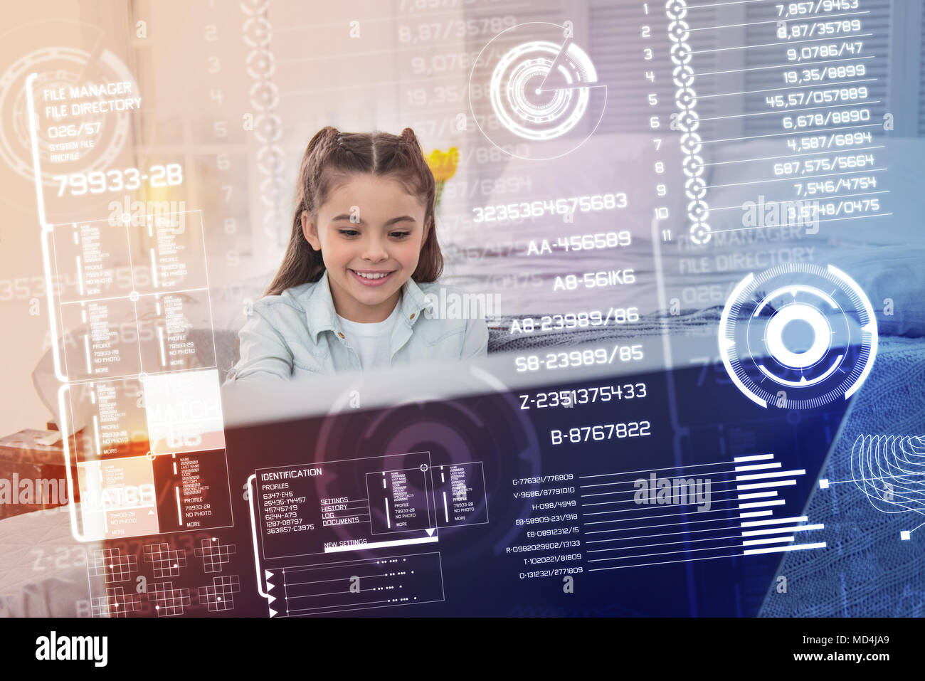 Positive girl smiling while sitting in front of a modern computer Stock ...