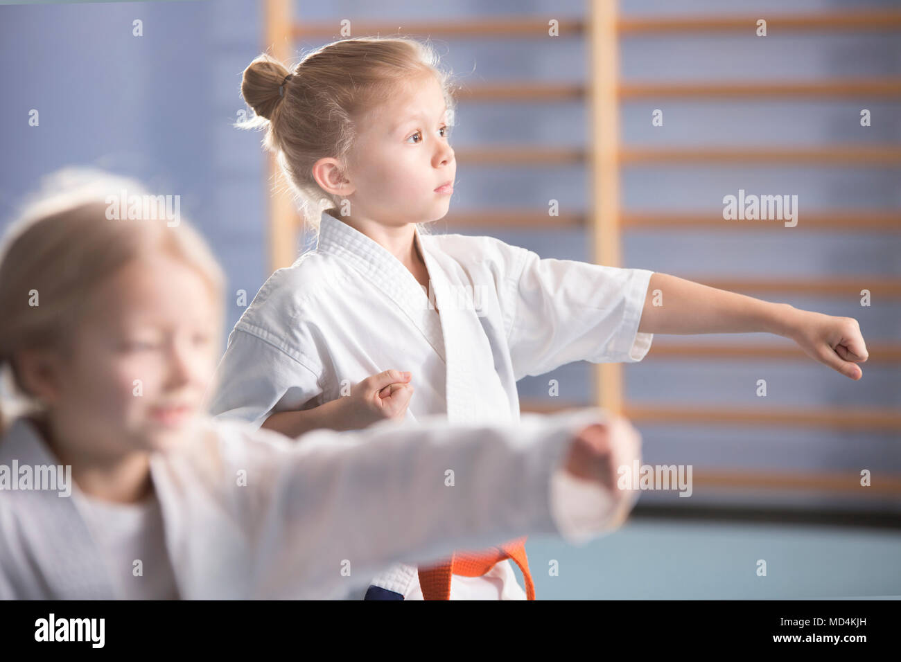 Young girl in kimono exercising during an extra-curricular karate class ...
