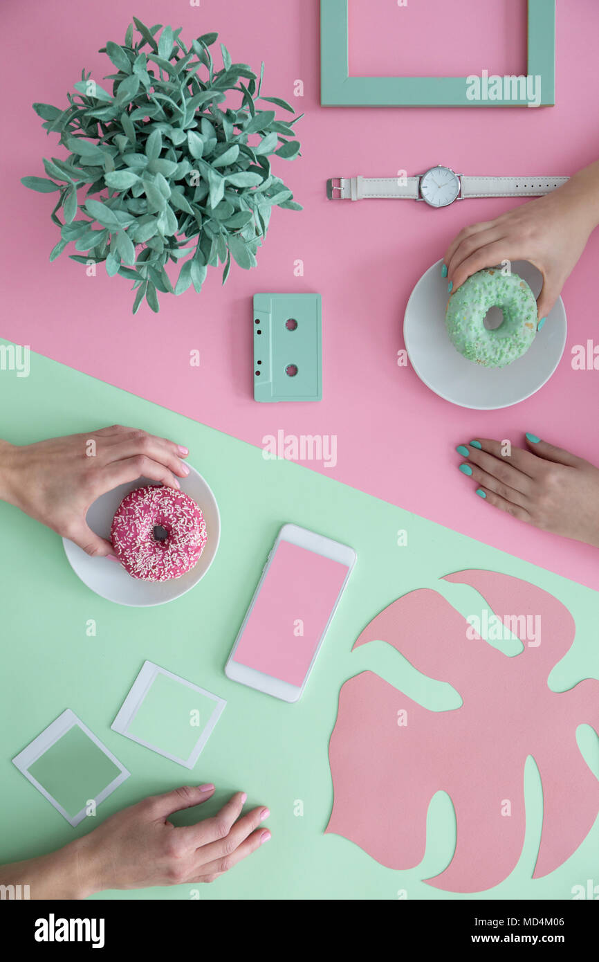 People eating pink and mint doughnuts on background with leaf, plant ...