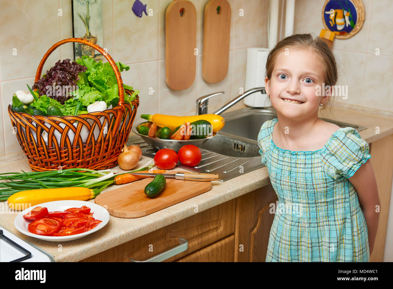 Child girl cooking in home kitchen. Basket of vegetables and fresh ...