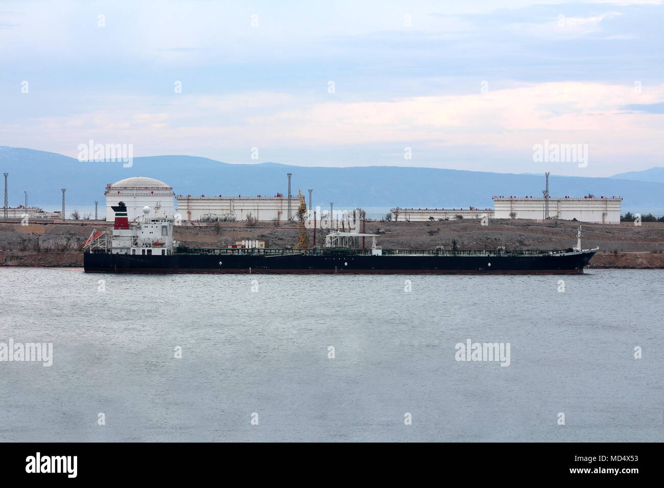 Oil tanker waiting to be connected and unloaded in small harbor ...