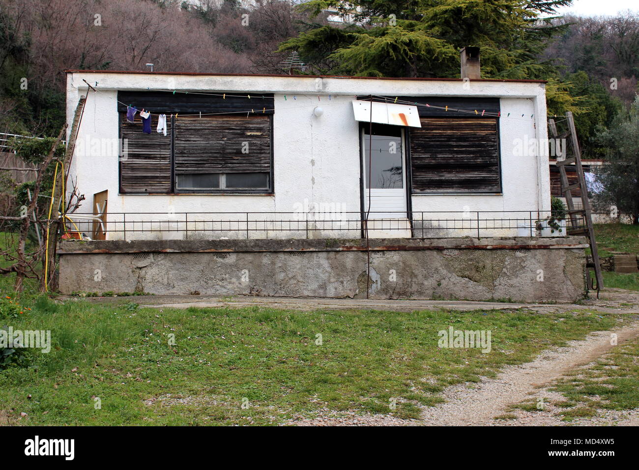 Small dilapidated house without roof with broken wooden blinds on ...
