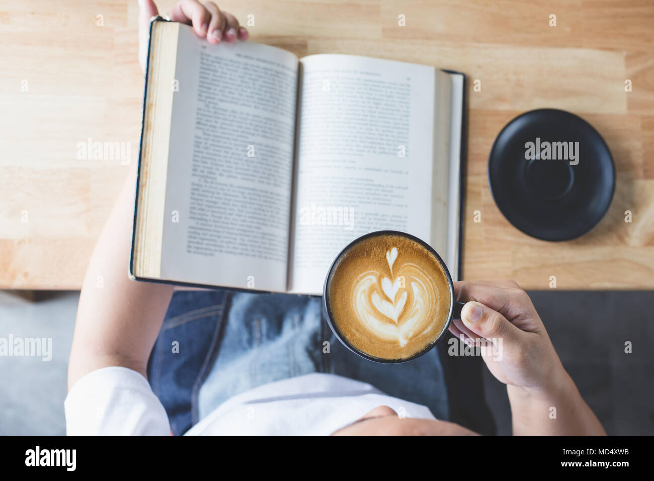 A girl reading book with drinking coffee latte with heart pattern in ...
