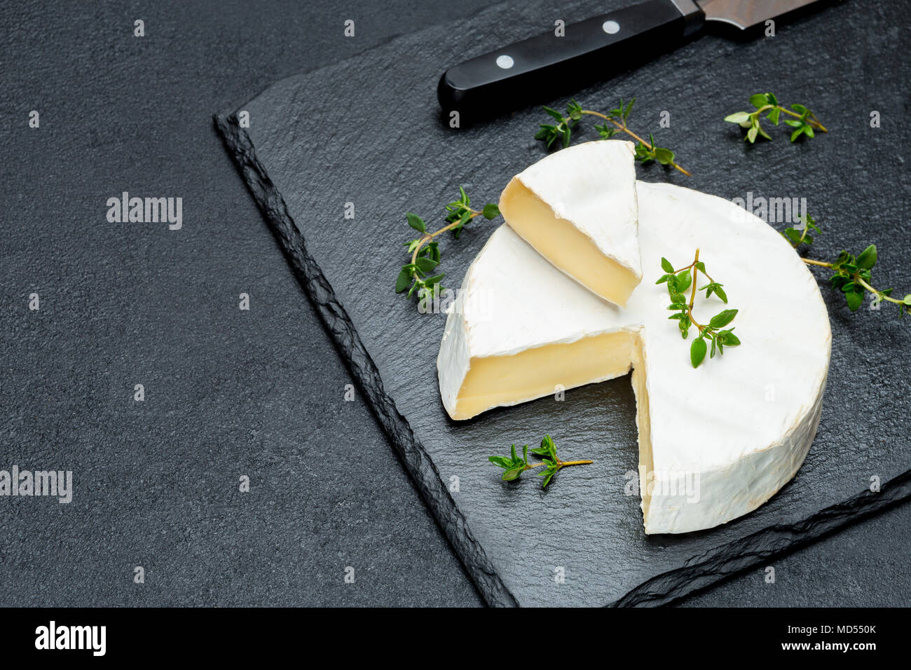 Camembert cheese and cut a slice on stone serving board Stock Photo - Alamy