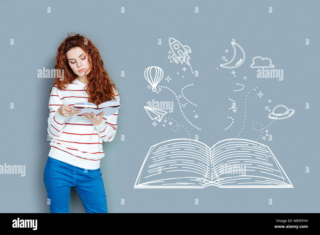 Young teacher looking interested while reading a book Stock Photo - Alamy