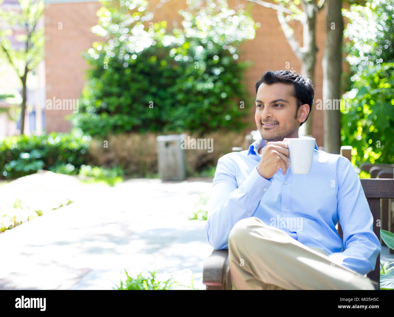 Closeup portrait, young business man drinking mug outside, sitting on ...