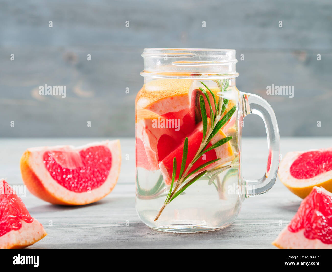 infused detox water with grapefruit and rosemary in mason jar on gray ...