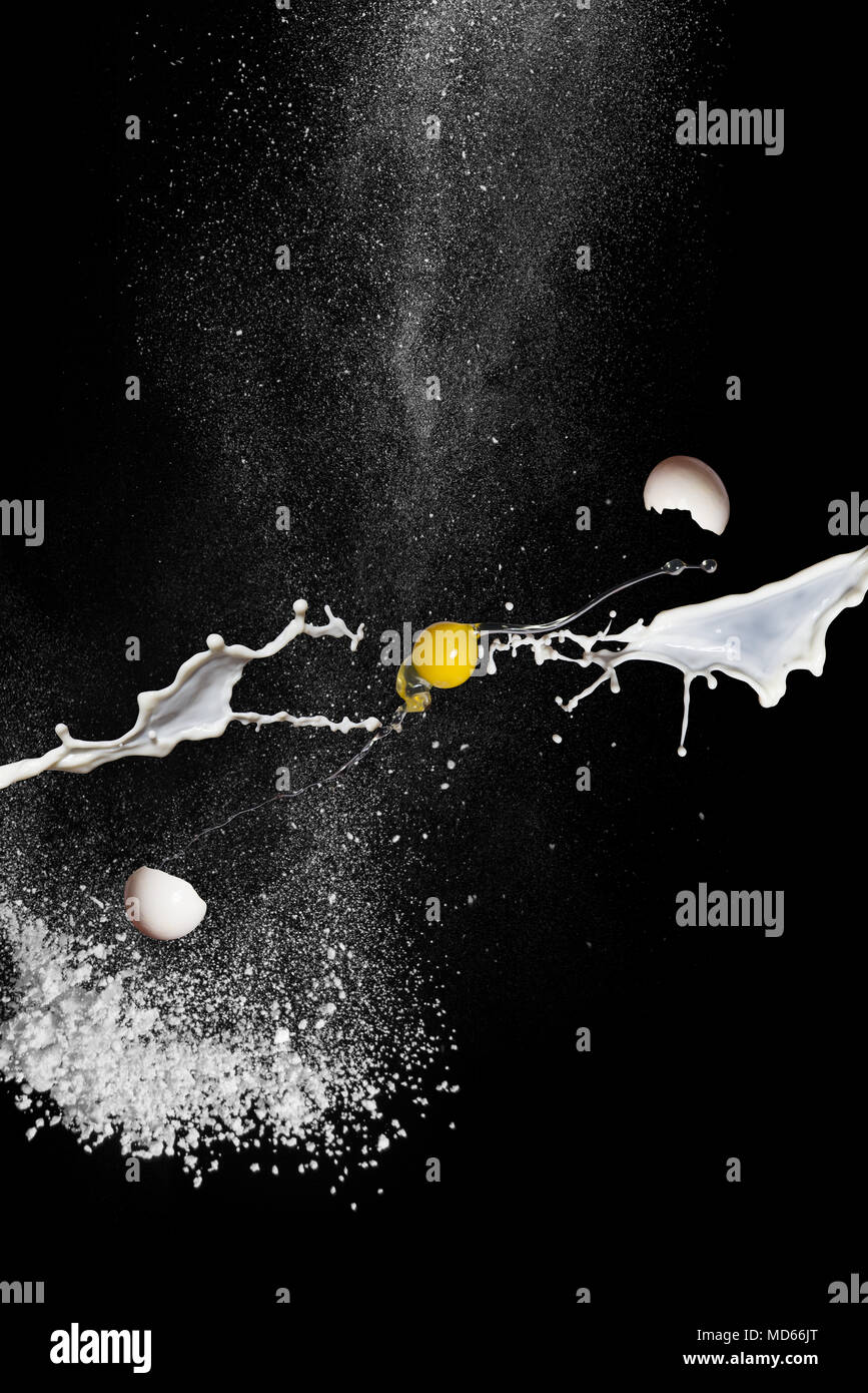 Cook breakfast. Egg in flight, milk and flour on black background ...