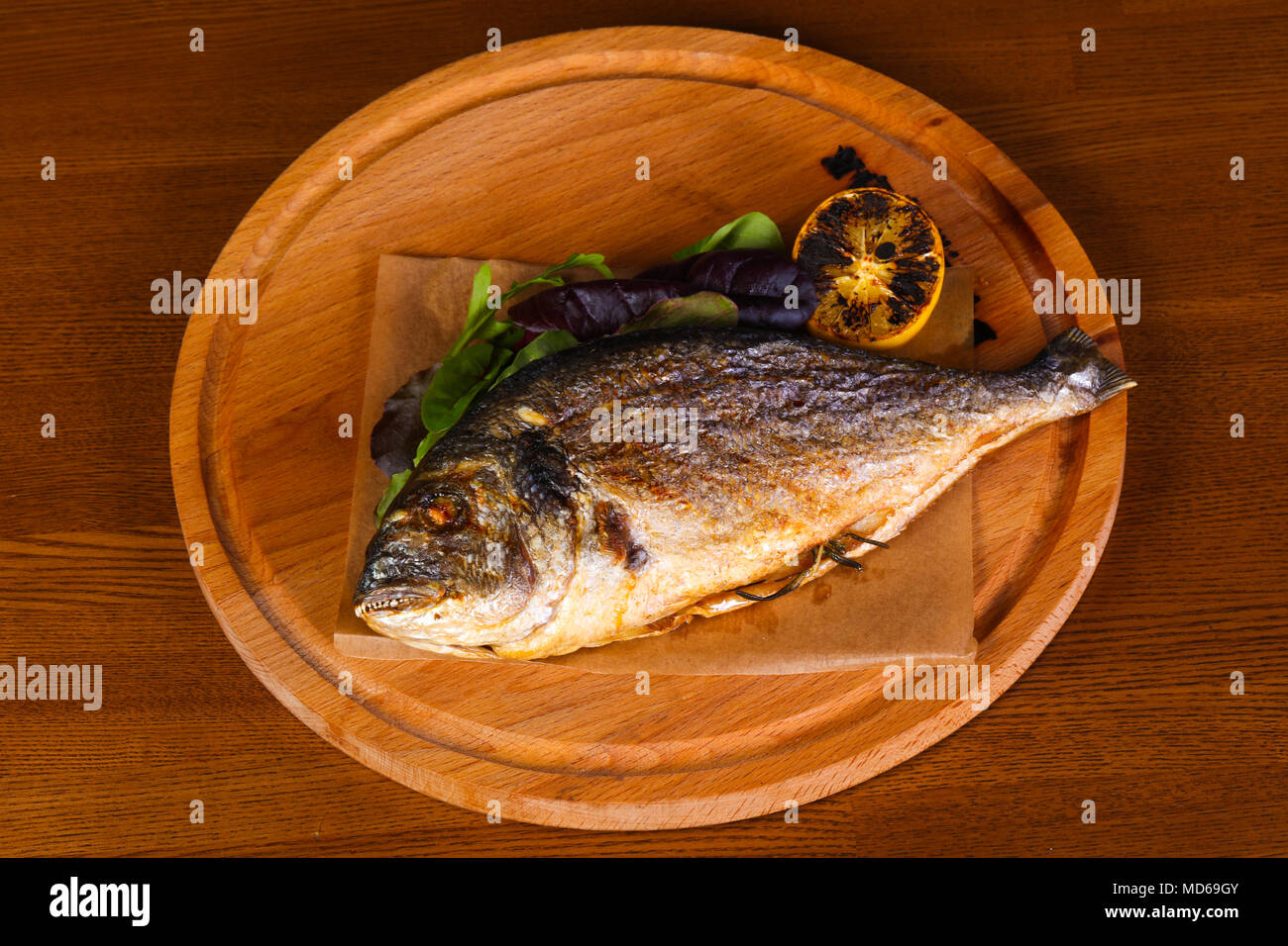 Grilled dorada with lemon over wooden background Stock Photo - Alamy