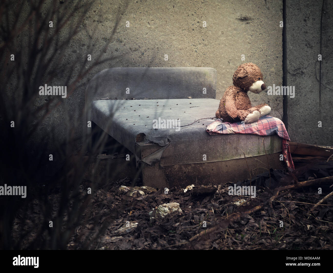 A toy bear on an old discarded bed in a dull place. The concept of ...